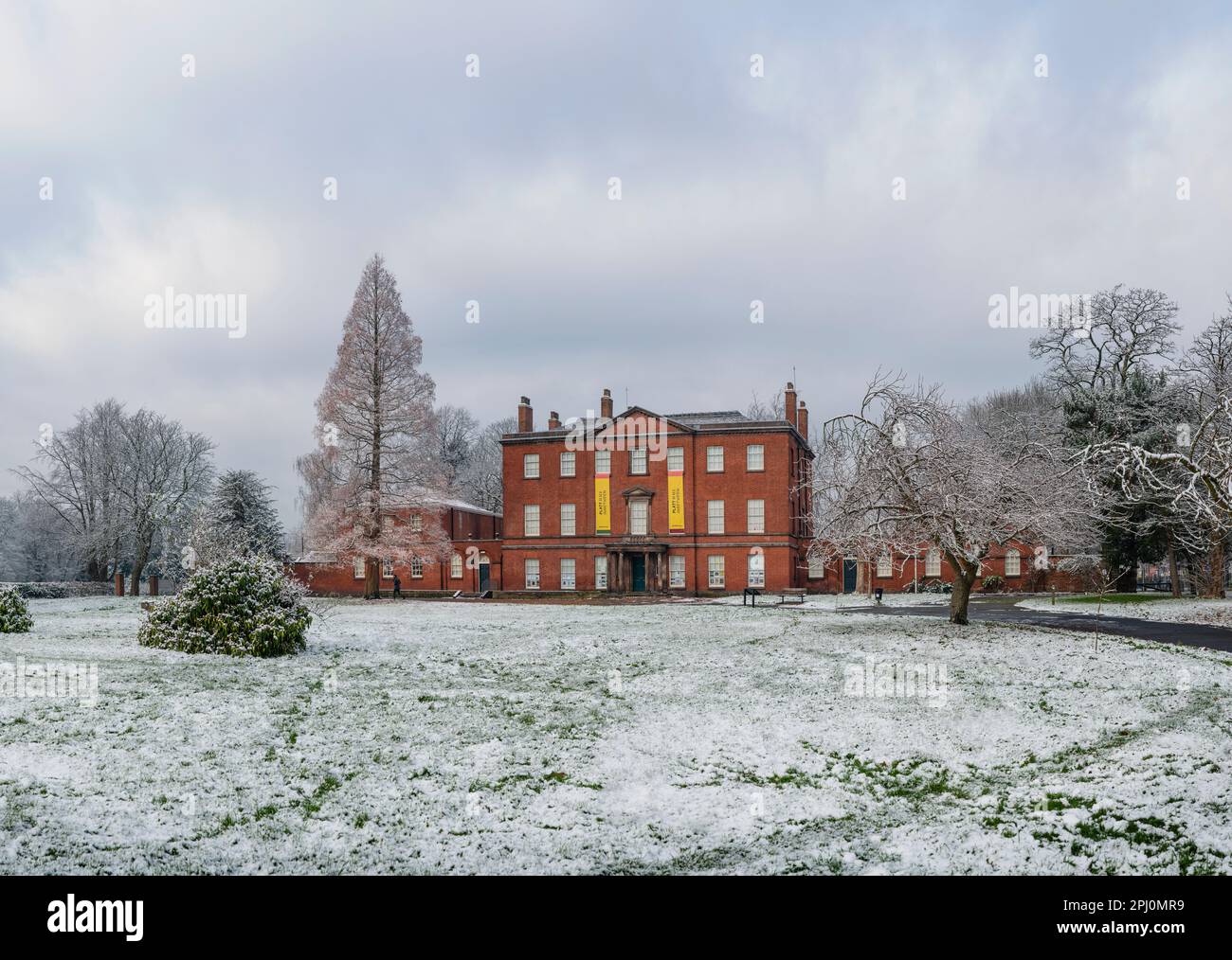 Platt Hall in Platt Fields Park, Manchester. A city park on a snowy winter morning. A mansion ...