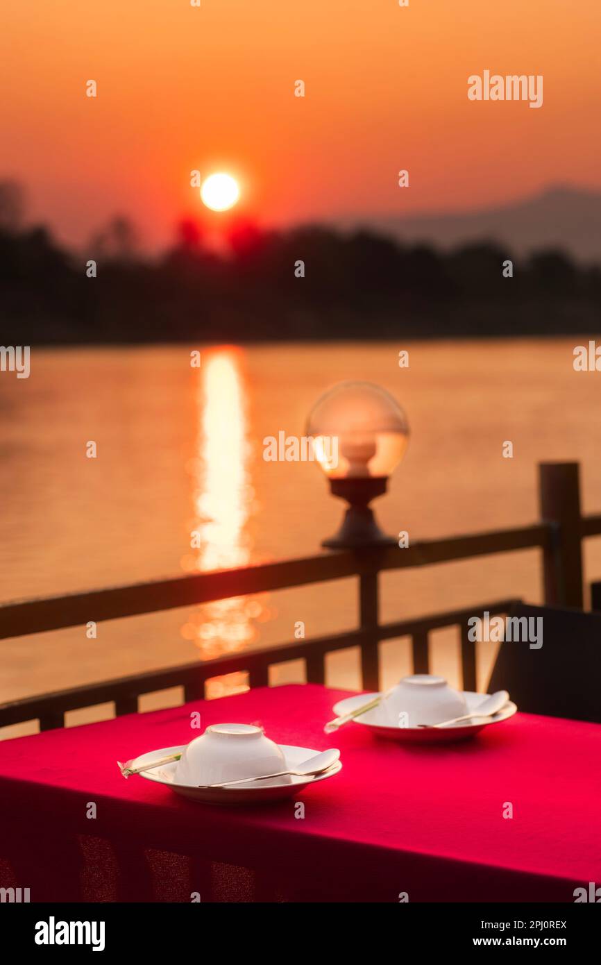 Dinner at riverside during sunset. Table and plates serving Stock Photo ...