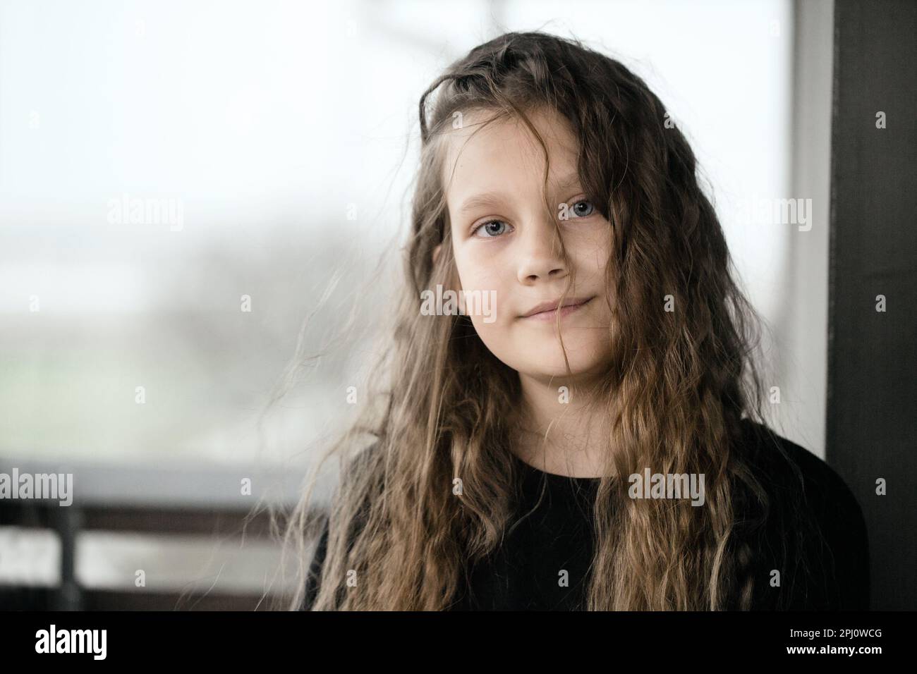 Friendly teenage girl with curly messy hair outdoors in windy weather ...