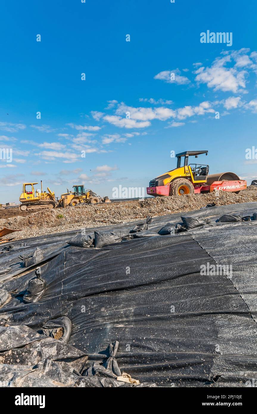 A bulldozer, a tractor, and a soil compactor are parked in the ...