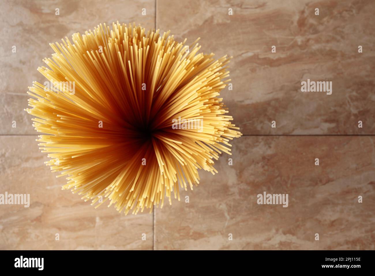 Yellow long spaghetti on a brown ceramic background. Yellow Italian ...