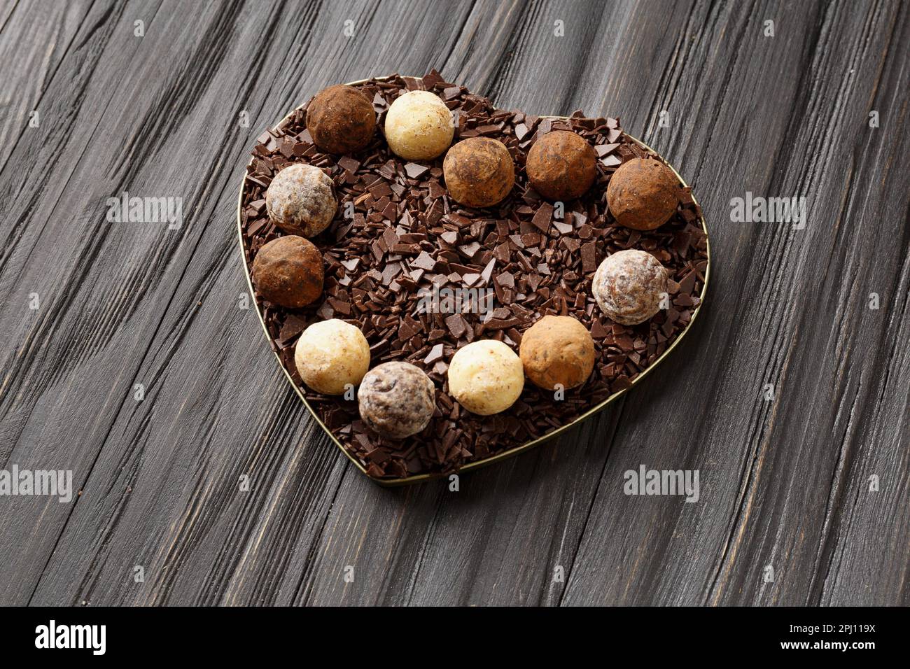 White, milk and dark chocolate truffles and chocolate chips in a heart ...