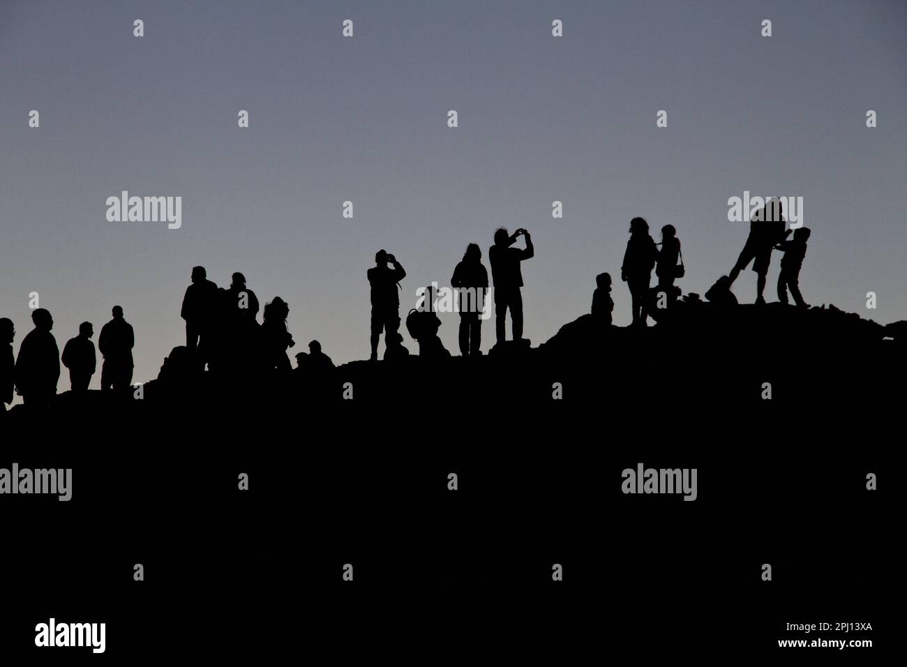 Dramatic silhouetted image of a group of people standing atop a rocky ...
