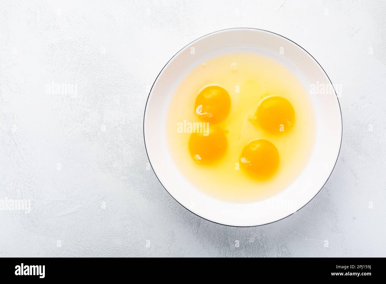Raw eggs, top view of four raw eggs yolk in bowl on white background Stock Photo - Alamy