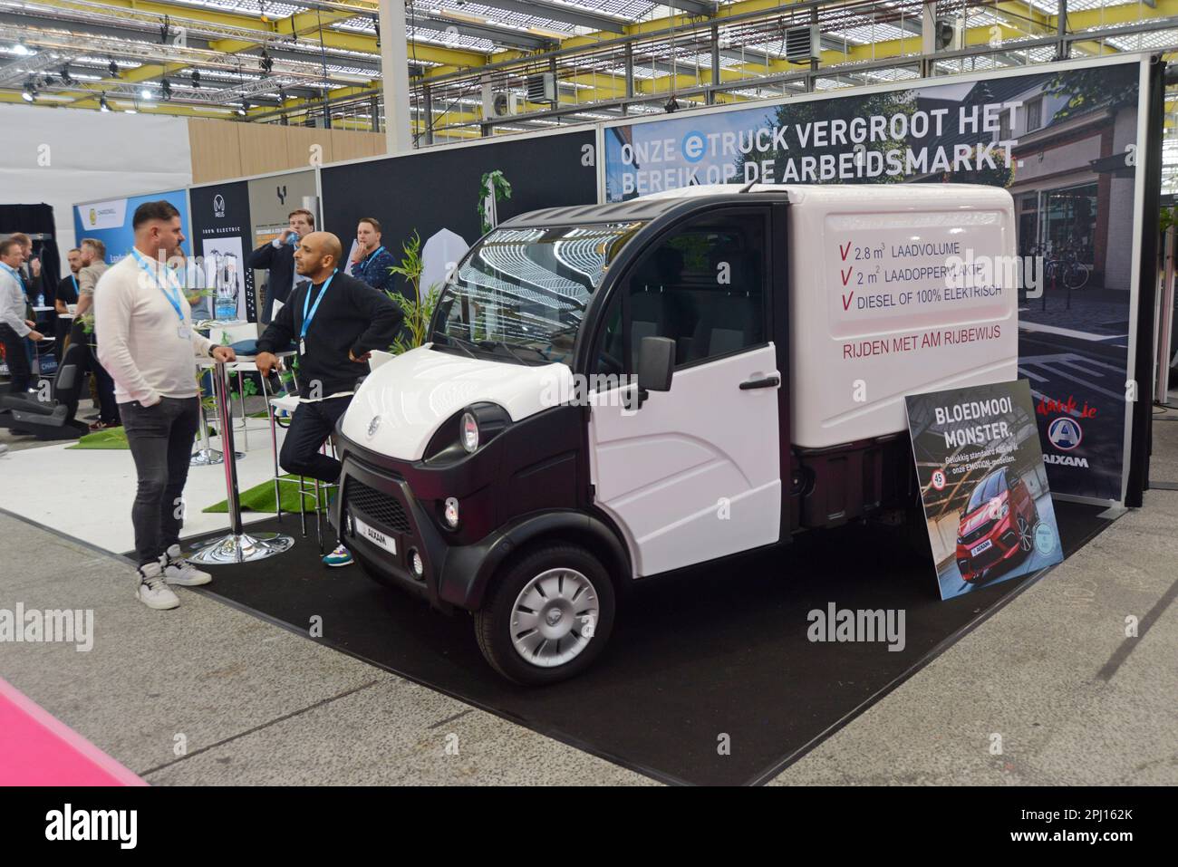 People looking at Aixim Quadricycle electric micro van on display at ...