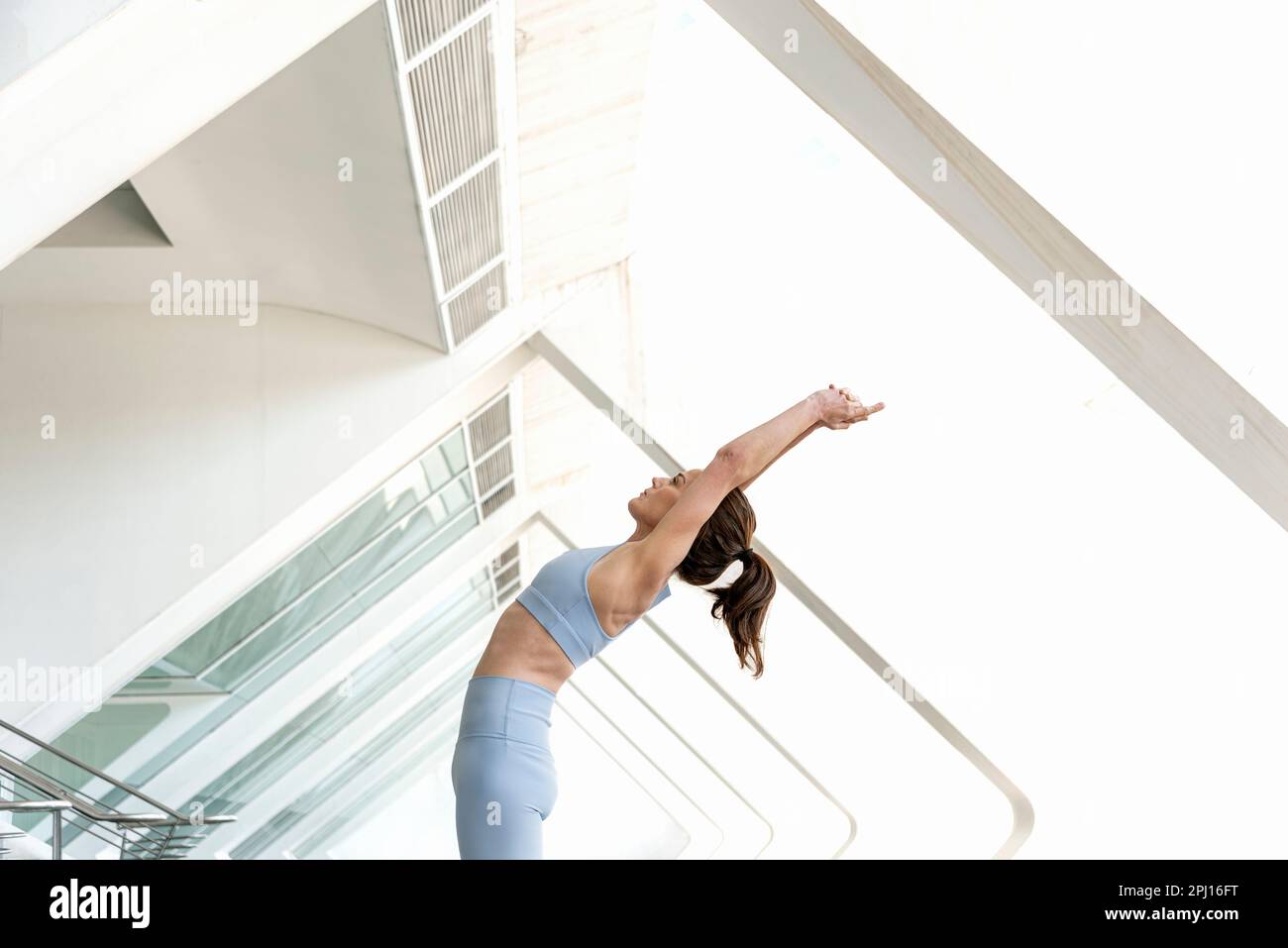 sporty woman doing standing backbend stretch outside in an urban ...