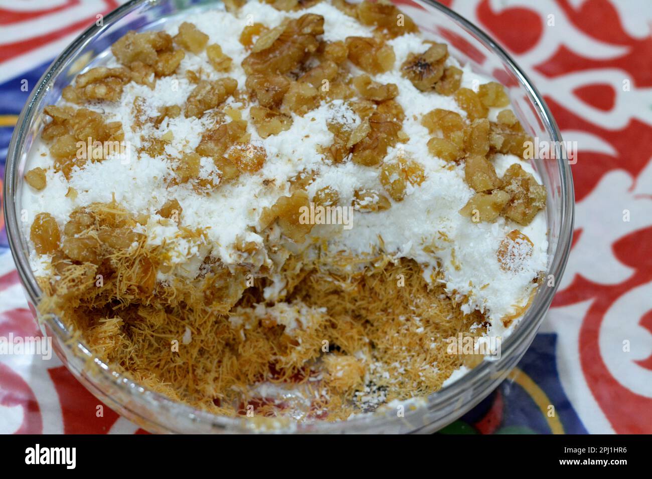 Konafa topped with whipped cream, raisins, walnuts, shredded coconut ...