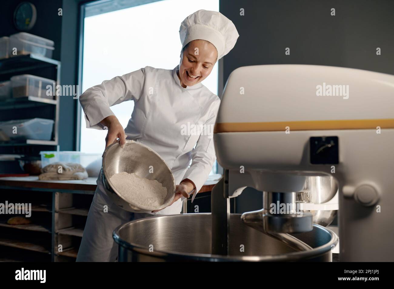 Woman baker pouring flour in mixing machine at bakery Stock Photo - Alamy