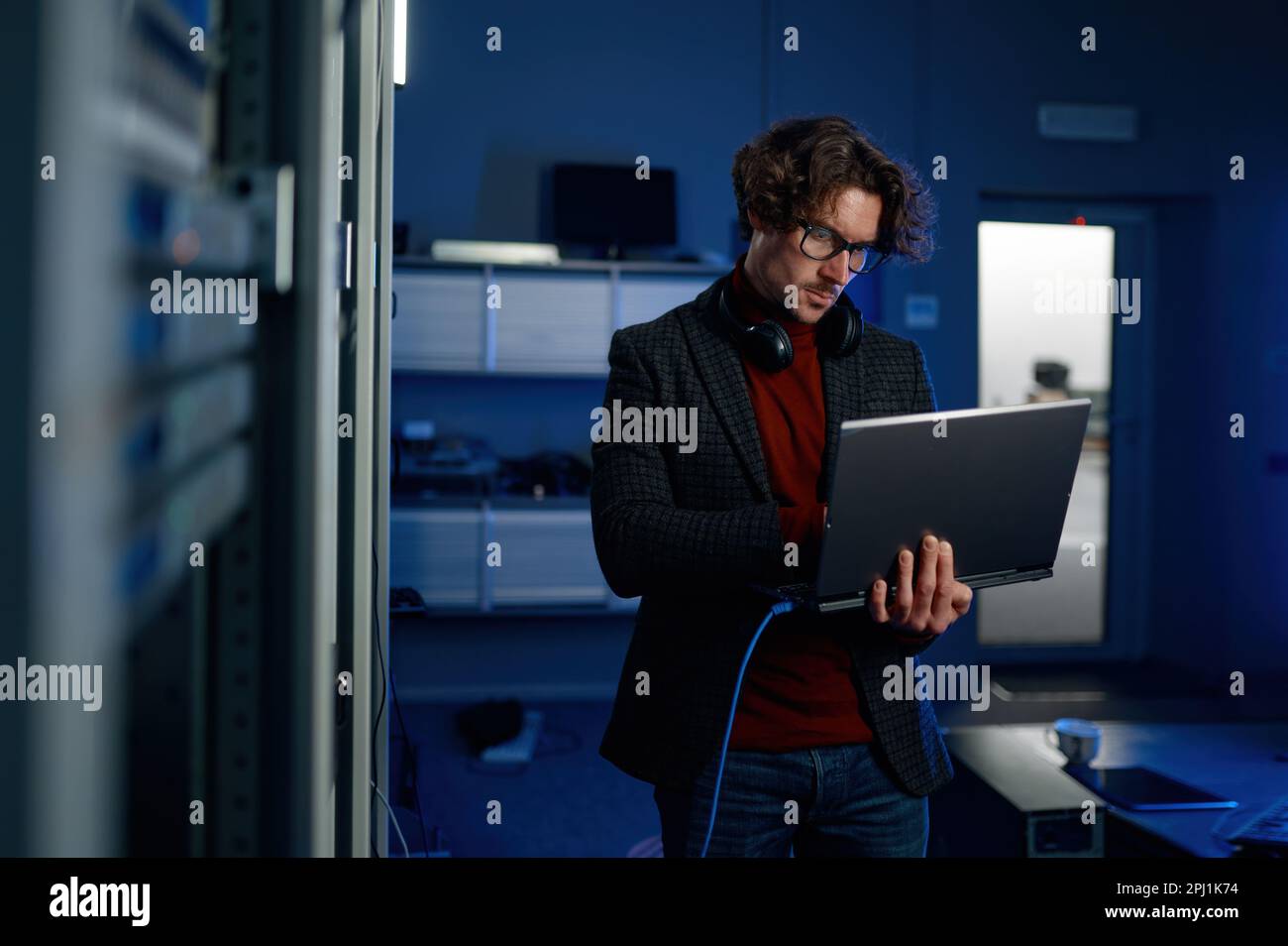 Data engineer holding laptop while working with supercomputer in server ...