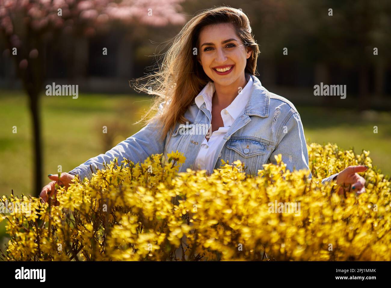 East asian young woman enjoying spring in a park with flowering trees ...