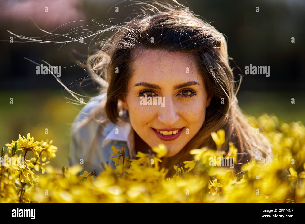 East asian young woman enjoying spring in a park with flowering trees ...