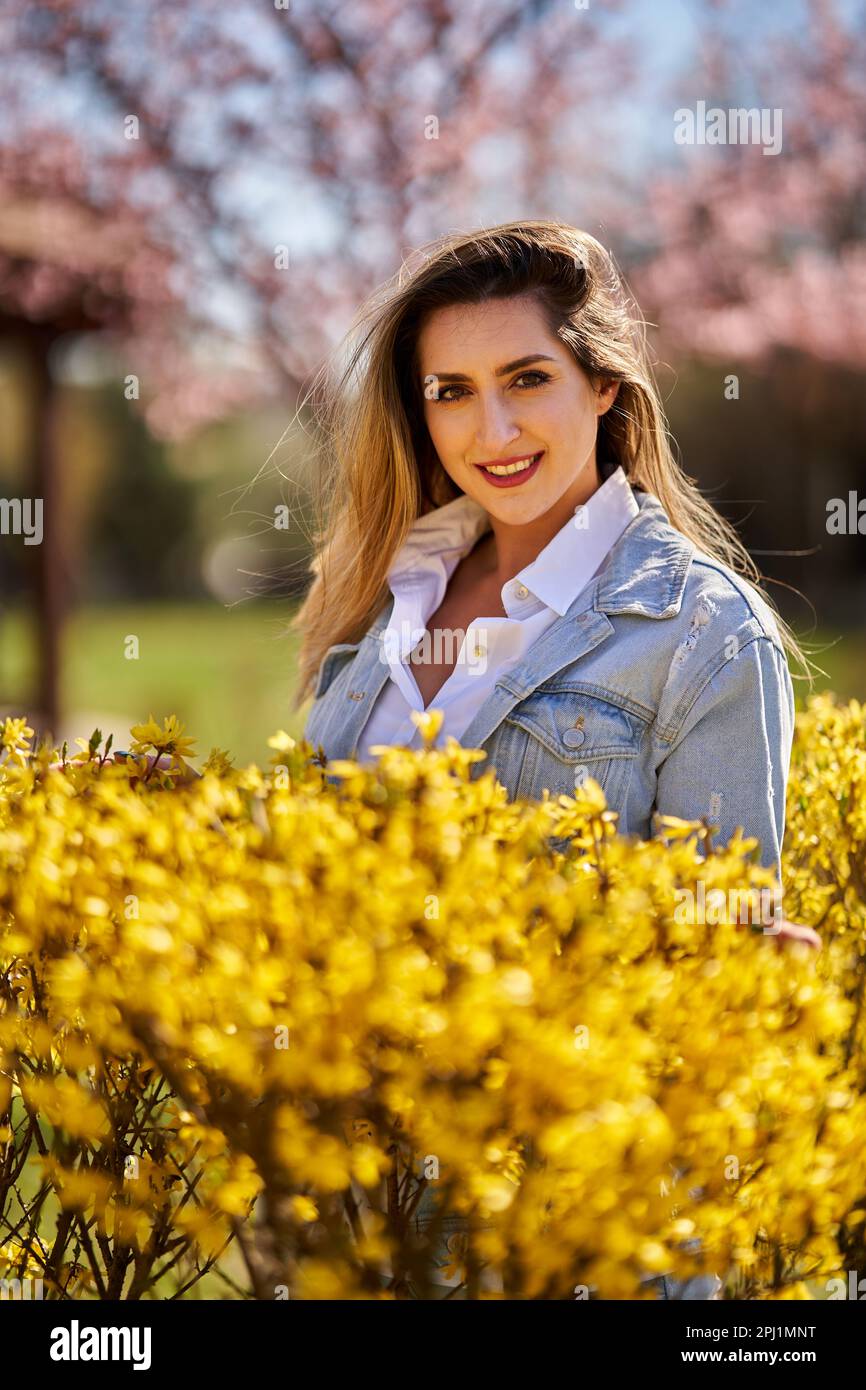 East asian young woman enjoying spring in a park with flowering trees ...