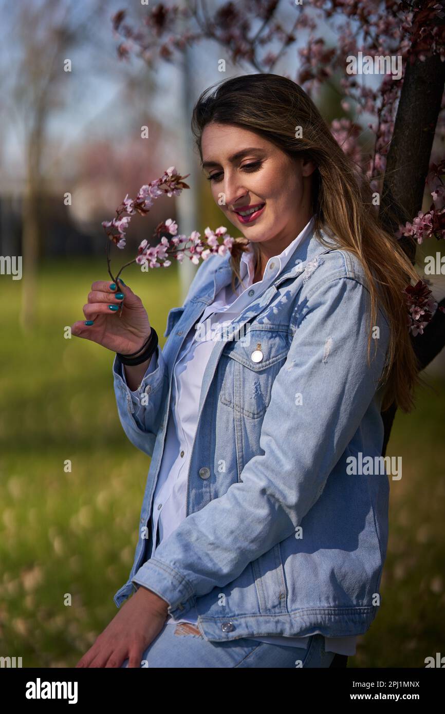 East asian young woman enjoying spring in a park with flowering trees ...