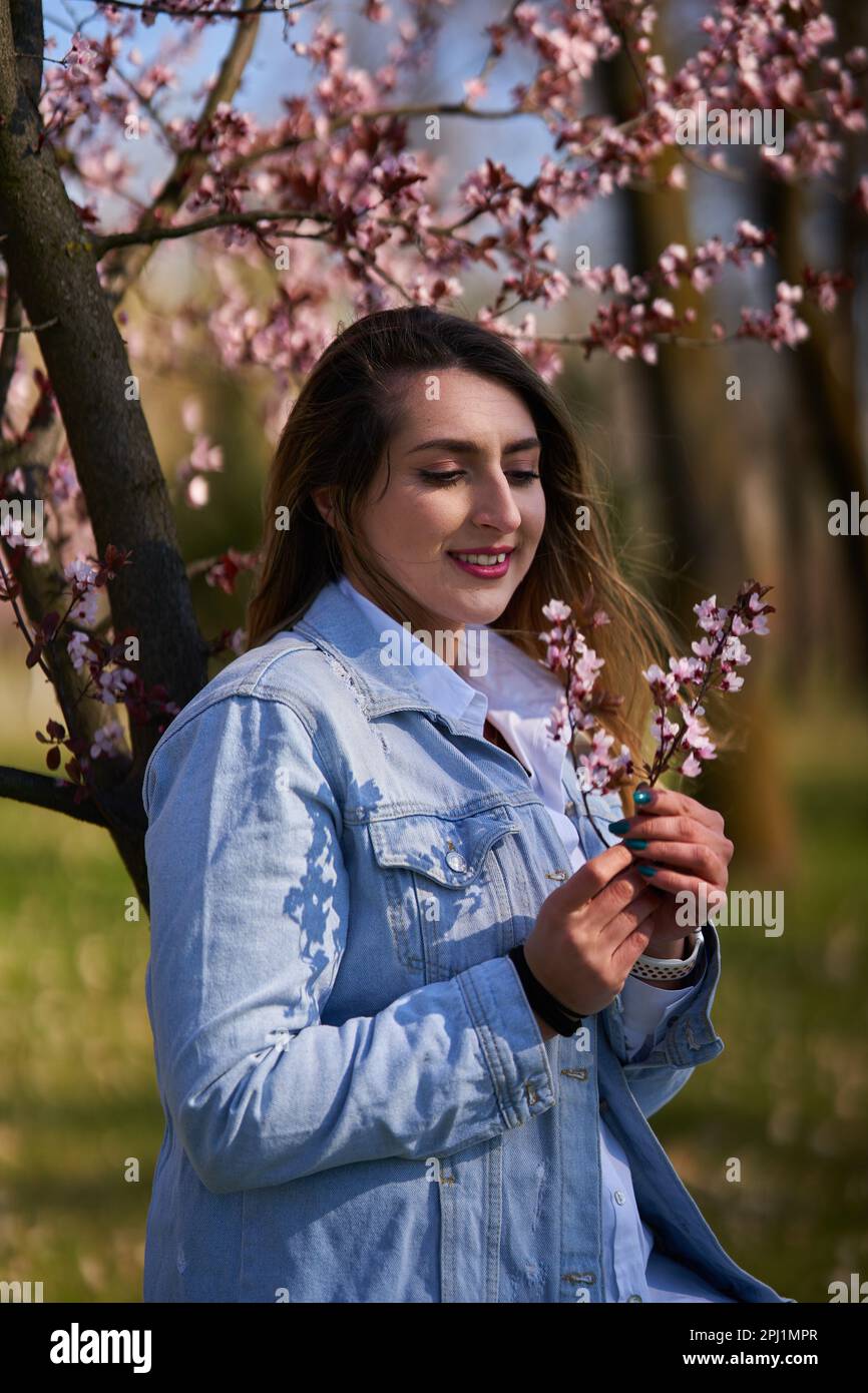 East asian young woman enjoying spring in a park with flowering trees ...