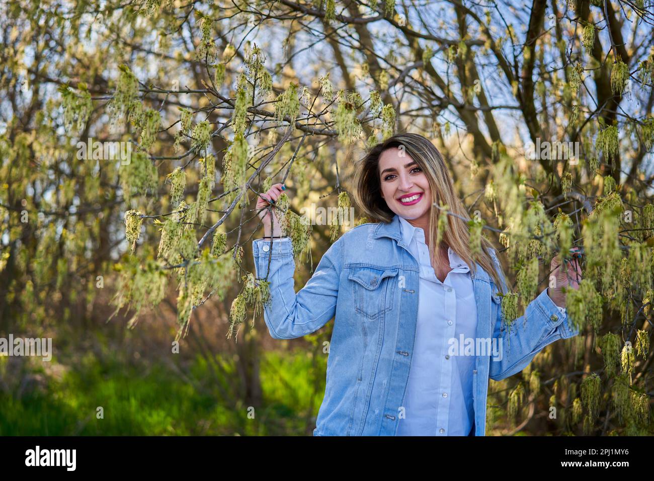 East asian young woman enjoying spring in a park with flowering trees ...