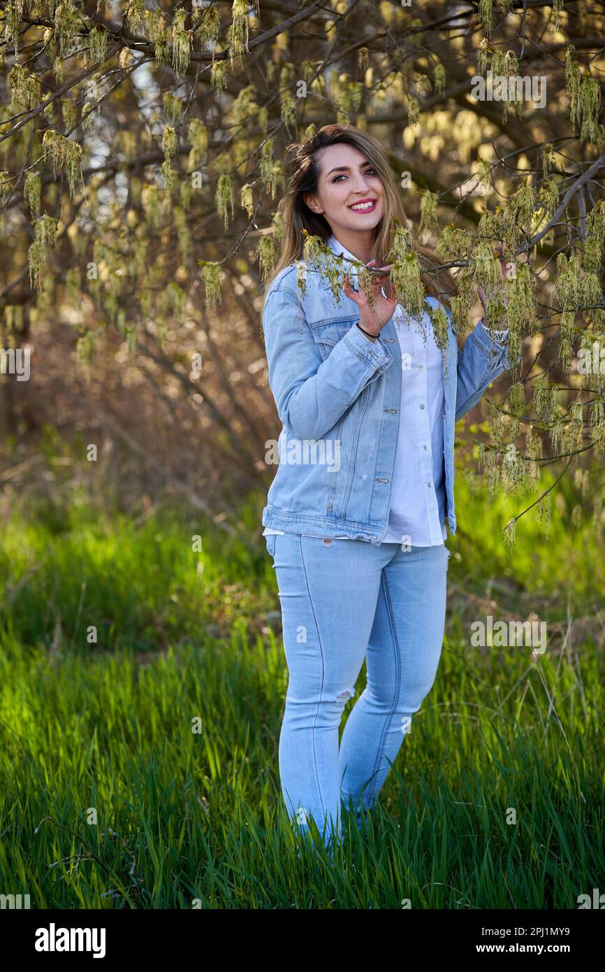 East asian young woman enjoying spring in a park with flowering trees ...