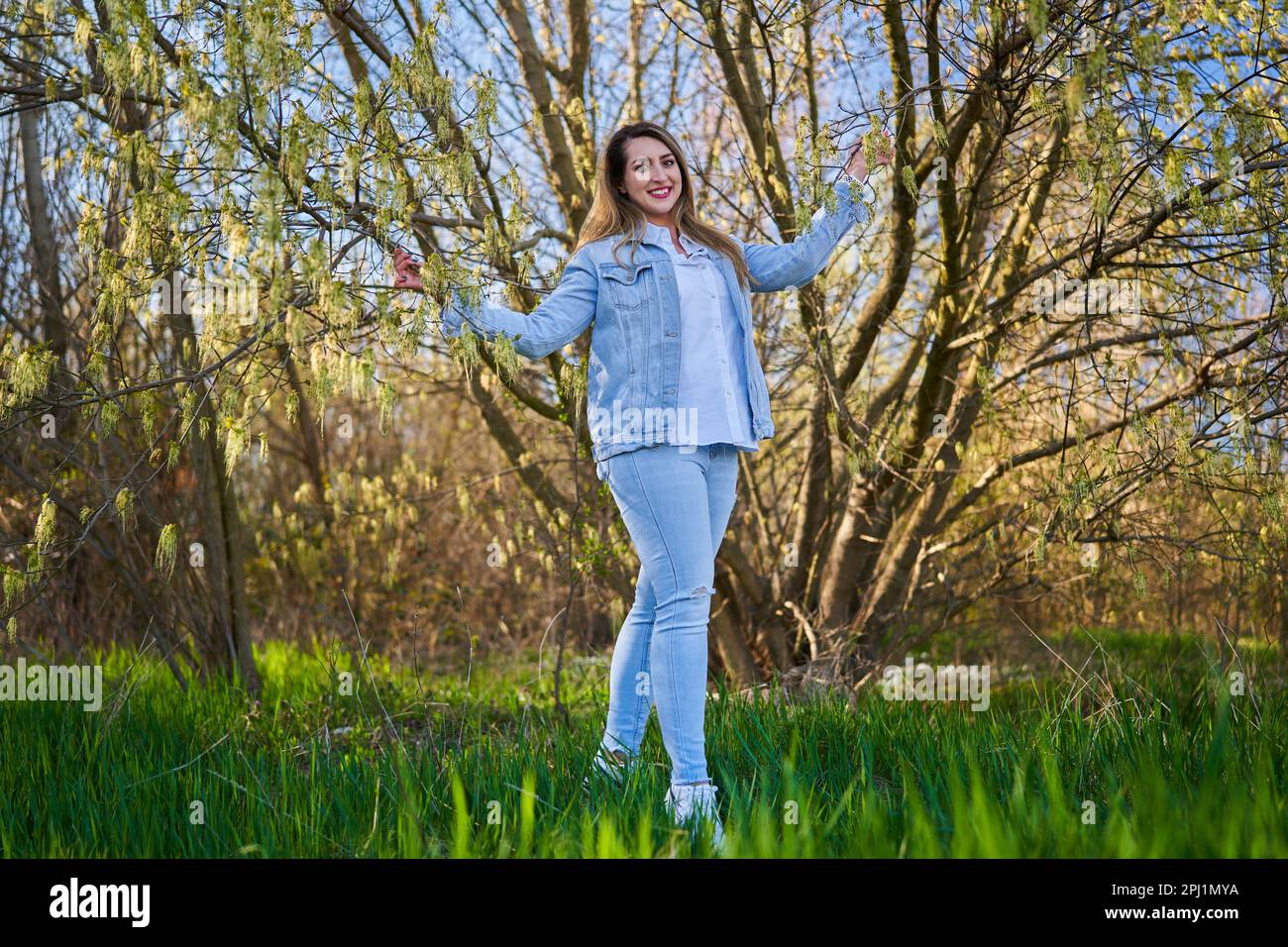 East asian young woman enjoying spring in a park with flowering trees ...