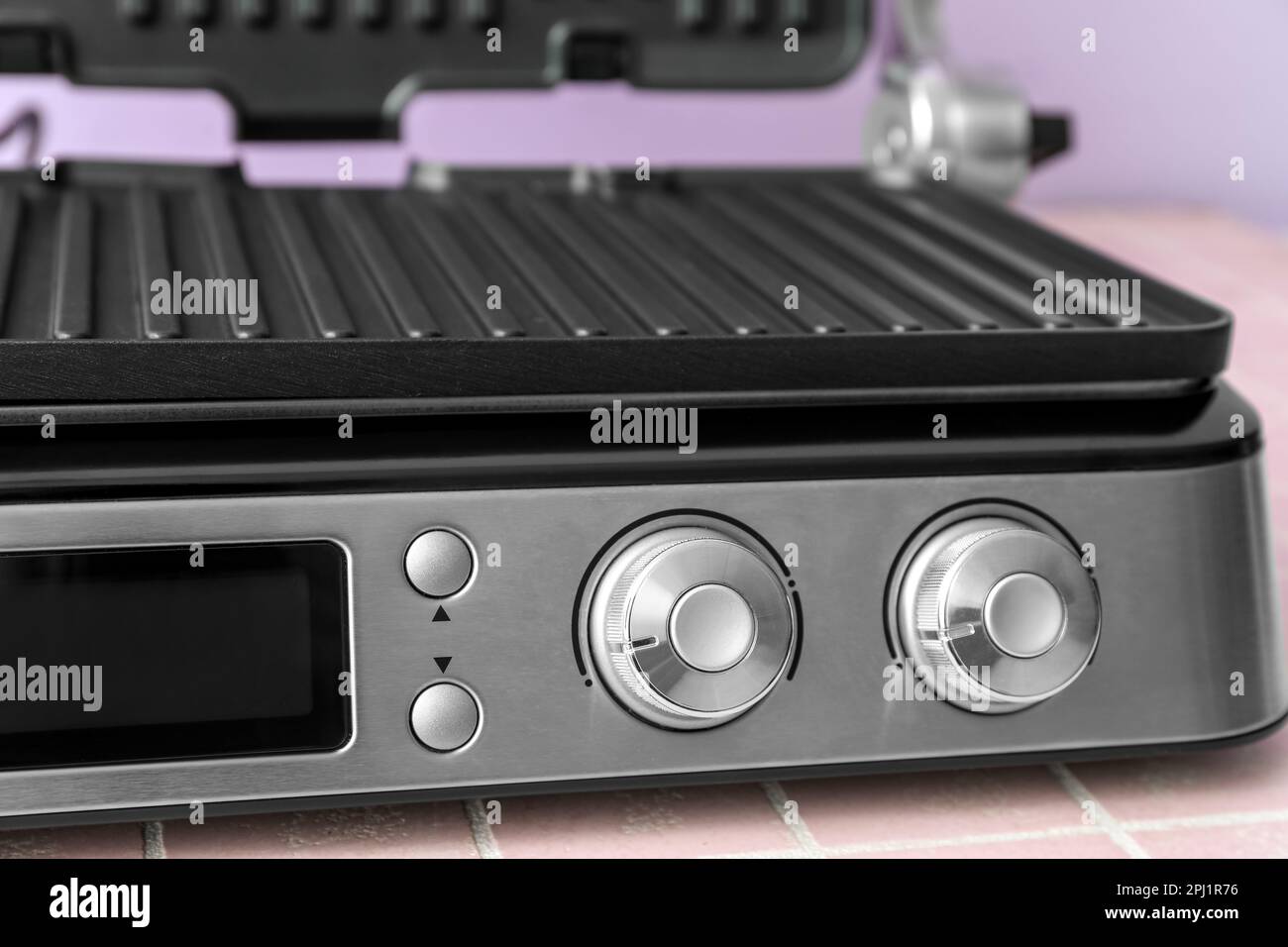 Control panel of modern electric grill on pink tile table, closeup ...