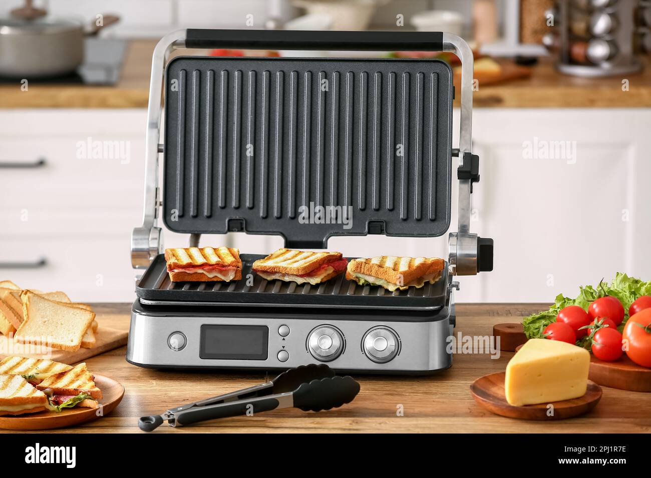 Modern electric grill with delicious sandwiches on kitchen counter ...