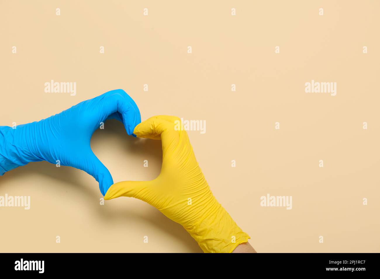 Doctor in medical gloves in colors of Ukrainian flag making heart with ...