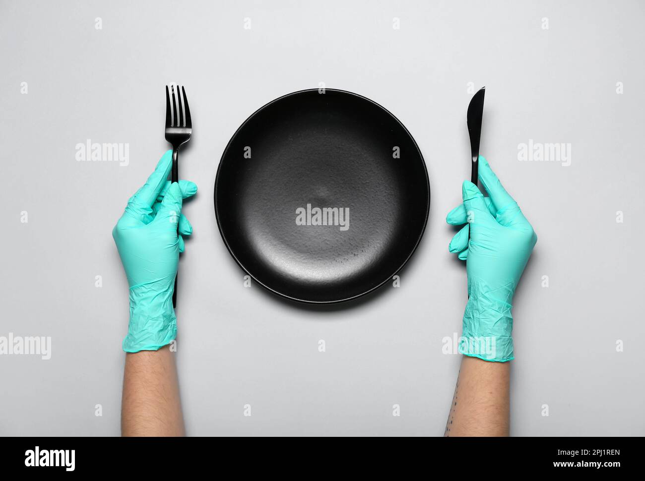 Chef in rubber gloves with cutlery and plate on grey background Stock ...