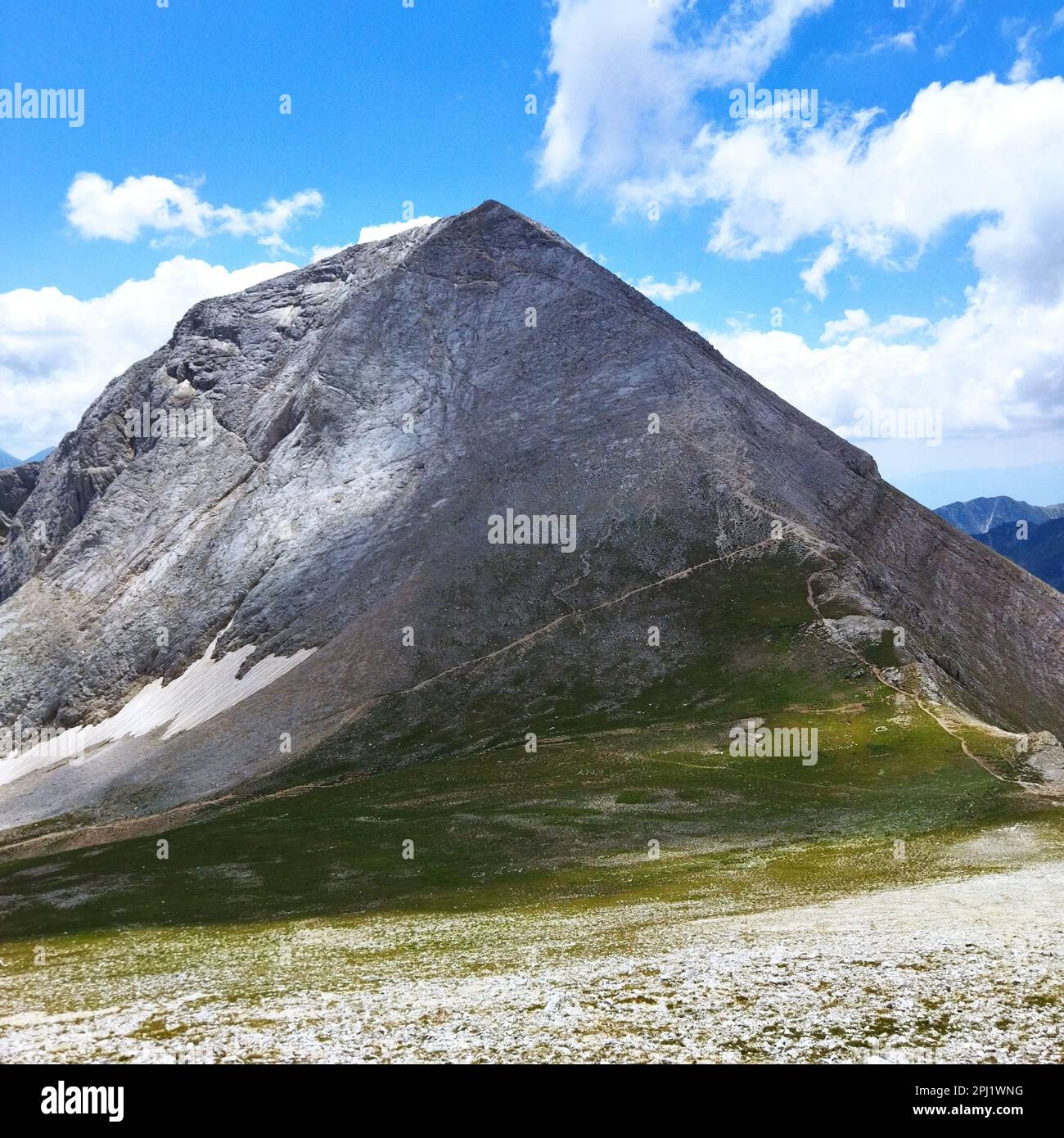 A scenic view of a mountain peak towering over a rolling landscape of ...