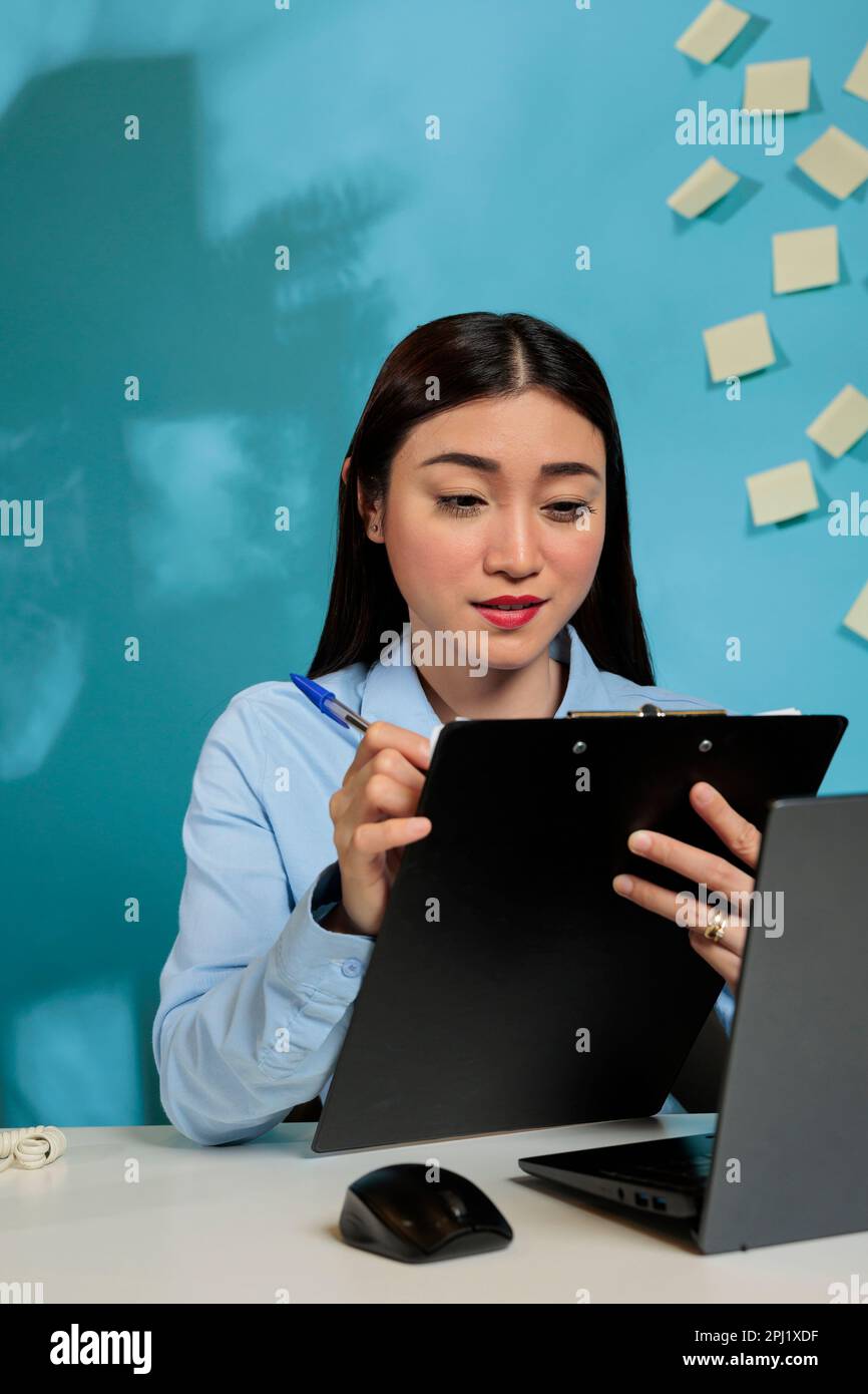Employee working from office looking at paperwork on clipboard ...
