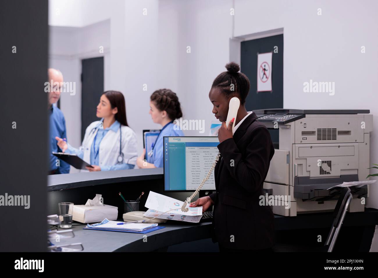 African american receptionist talking at landline phone with remote ...