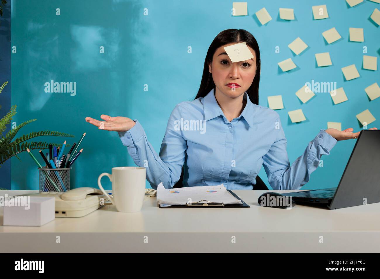 Insecure and doubtful startup worker, shrugging her arms while sitting ...