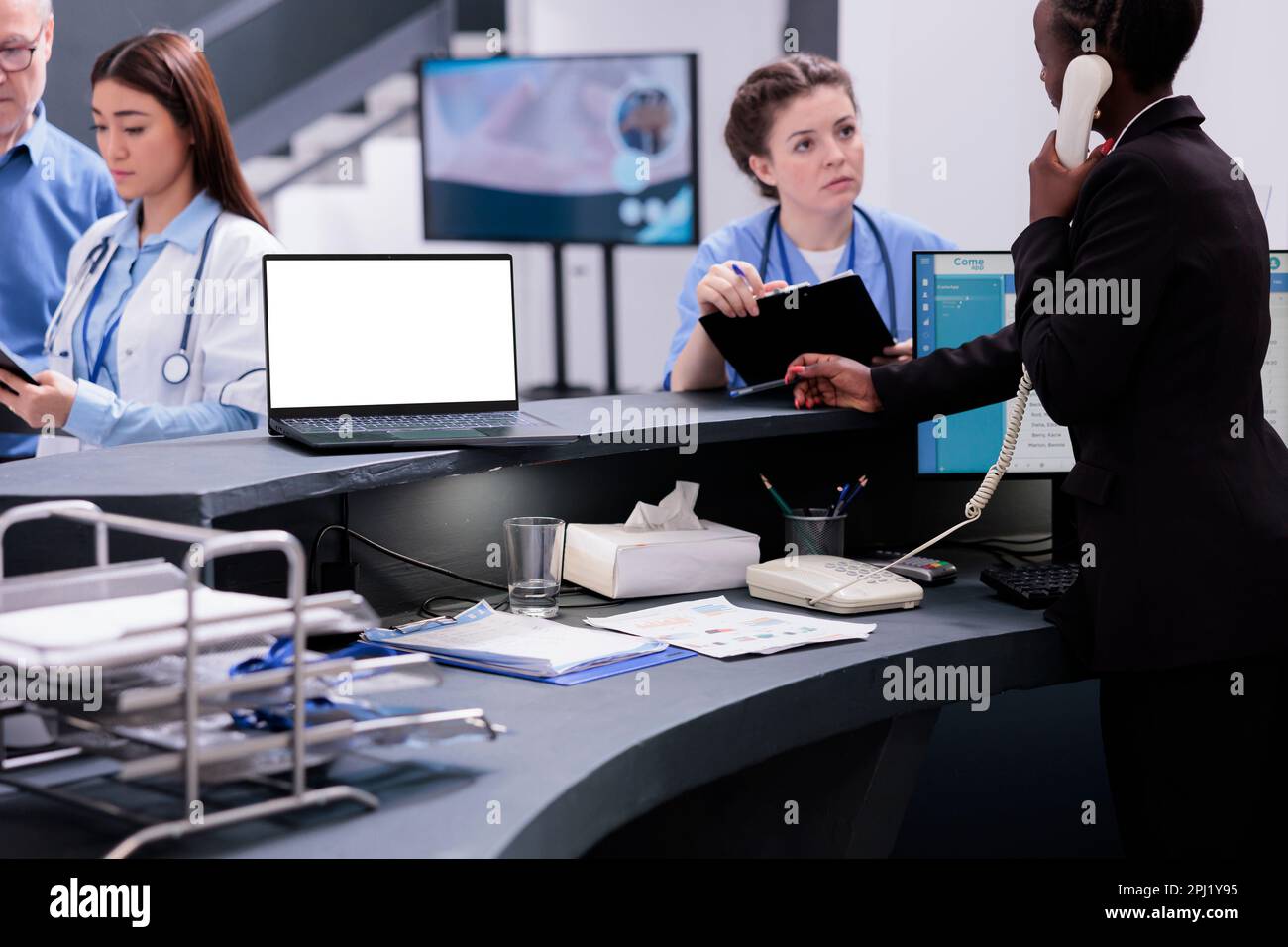 Nurse and receptionist working at patient treatment discussing illness ...