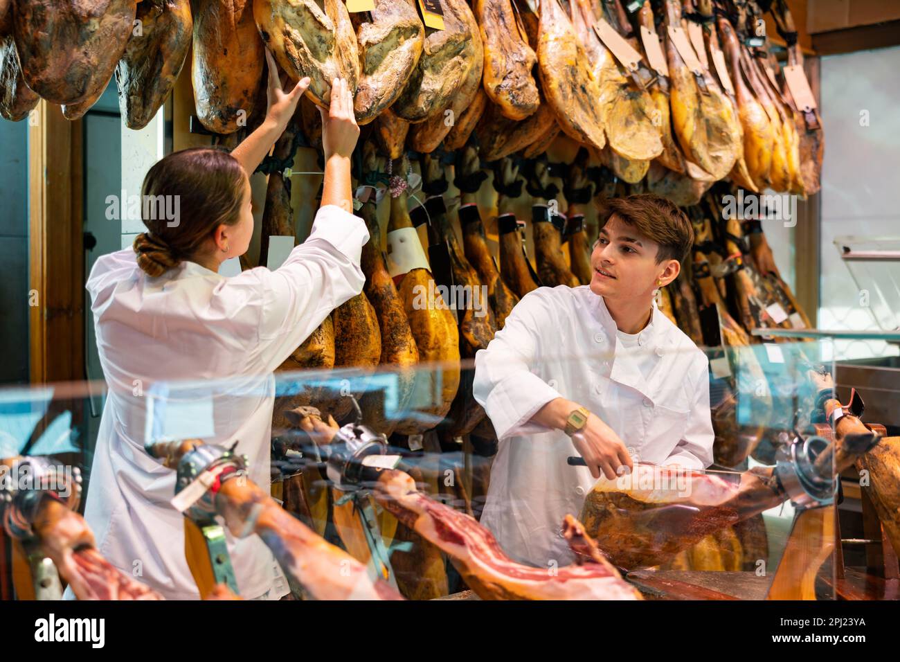 Young couple work together in butcher shop - they cut traditional ...
