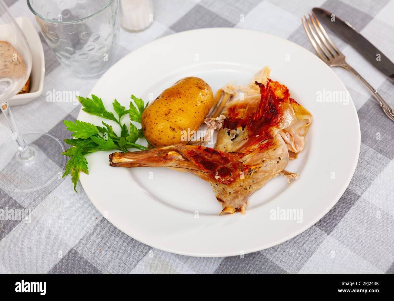 Roasted rabbit leg with side dish of boiled potatoes in skins Stock ...