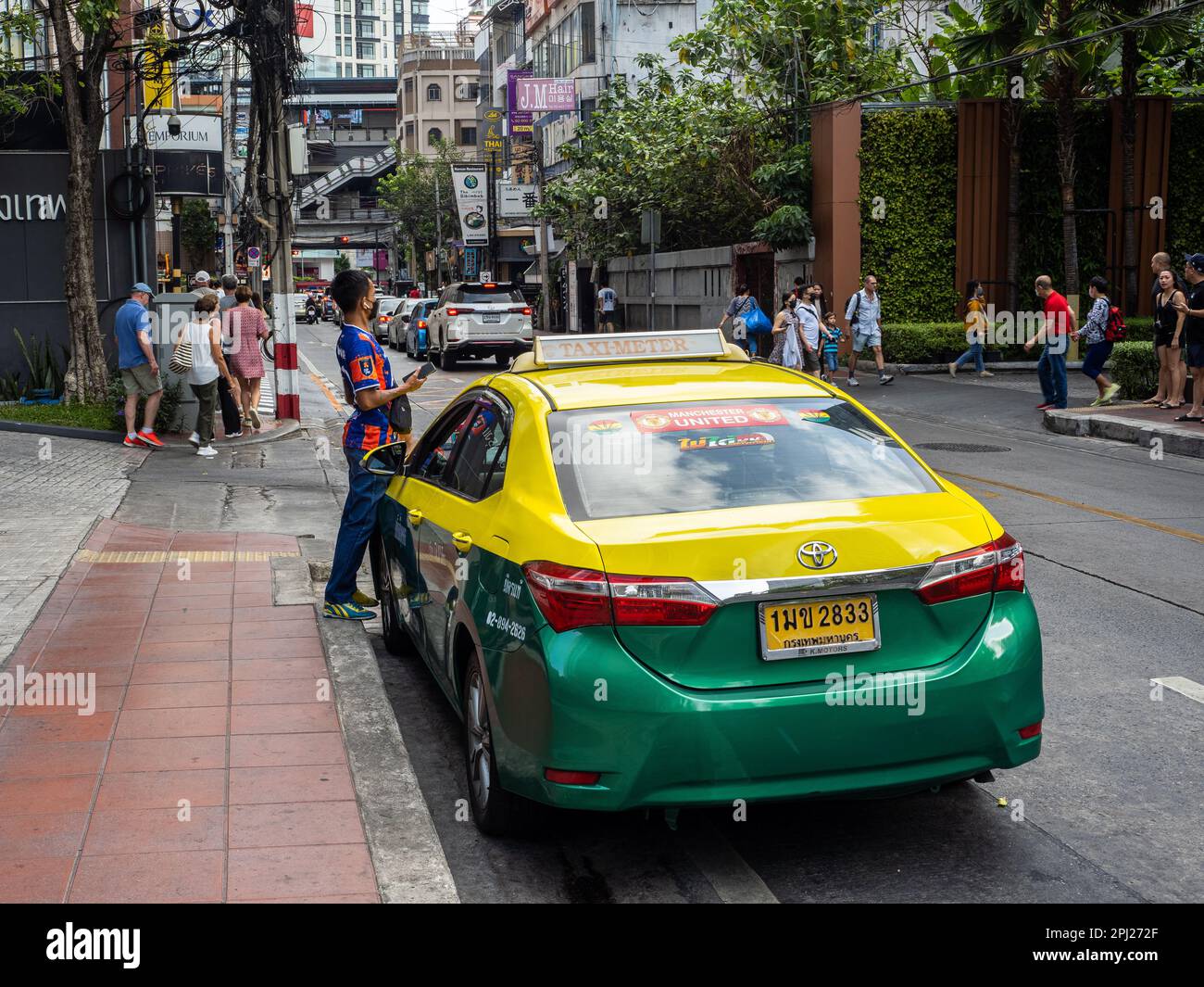 In the heart of Bangkok, a classic green and yellow taxi with its ...