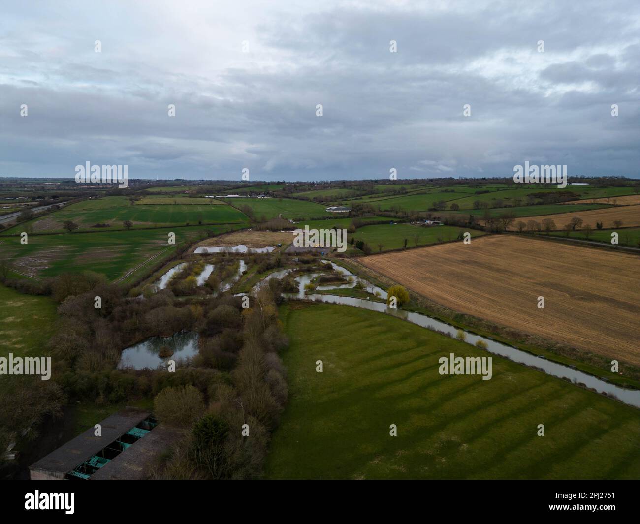 Aerial view of a small canal passing through a rural landscape of A45 ...