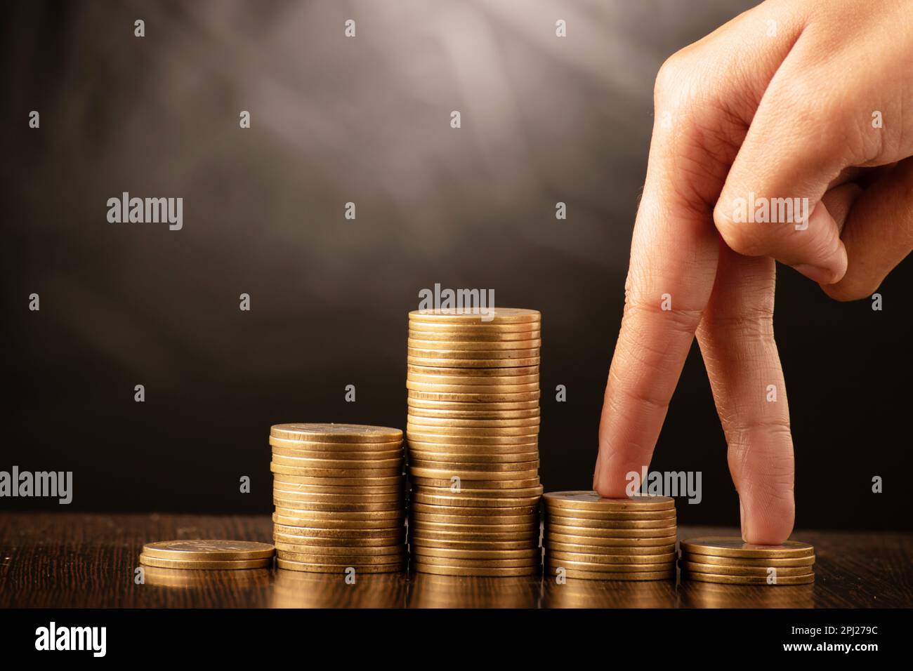 Finger stepping to coin stack Stock Photo - Alamy