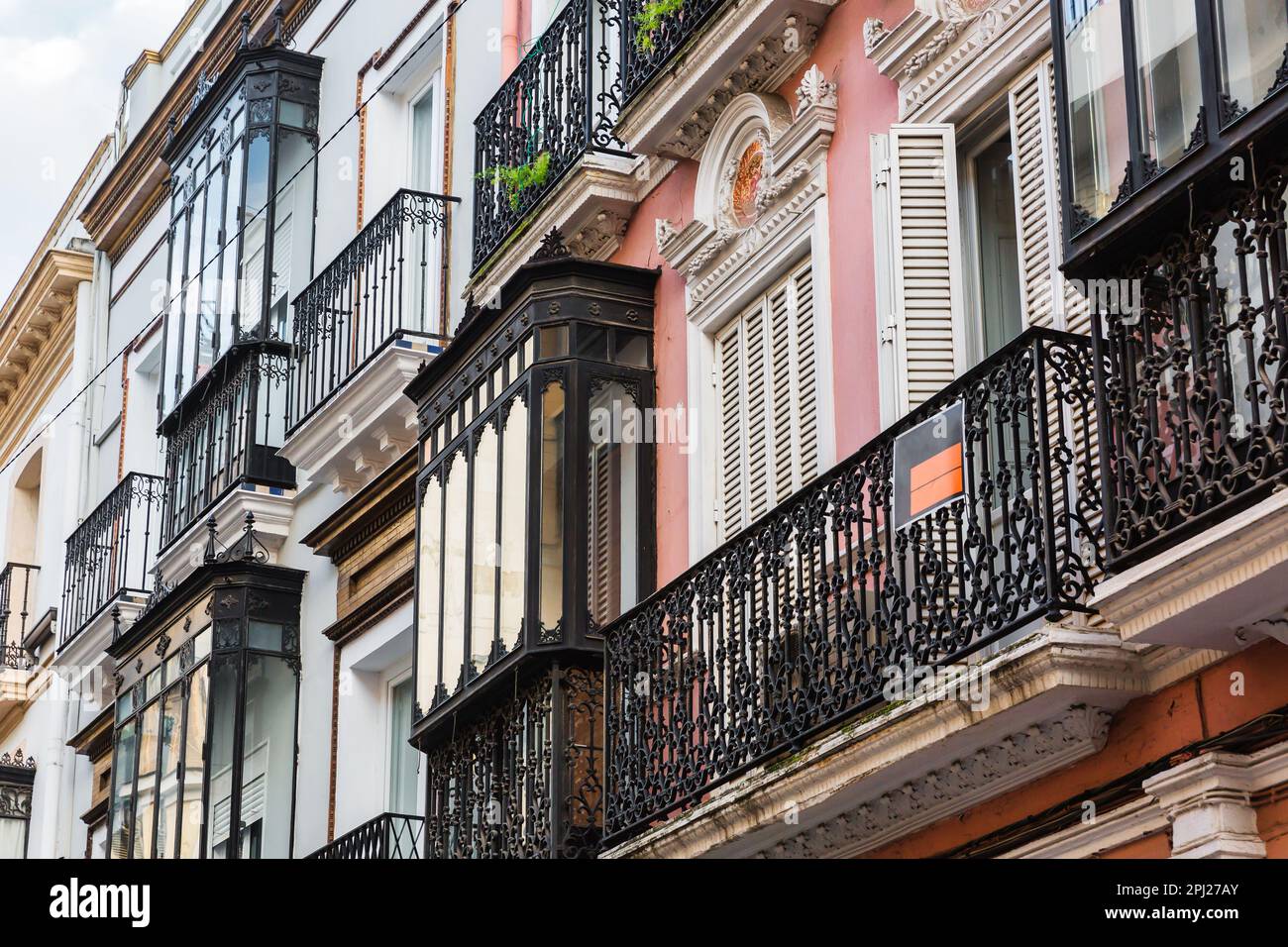 Facade with bay windows and balconies of historic townhouses in Seville ...
