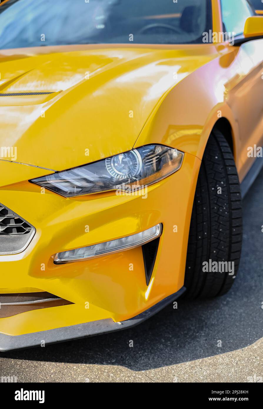 Part of front end of a yellow sport car, headlights and part of wheel ...