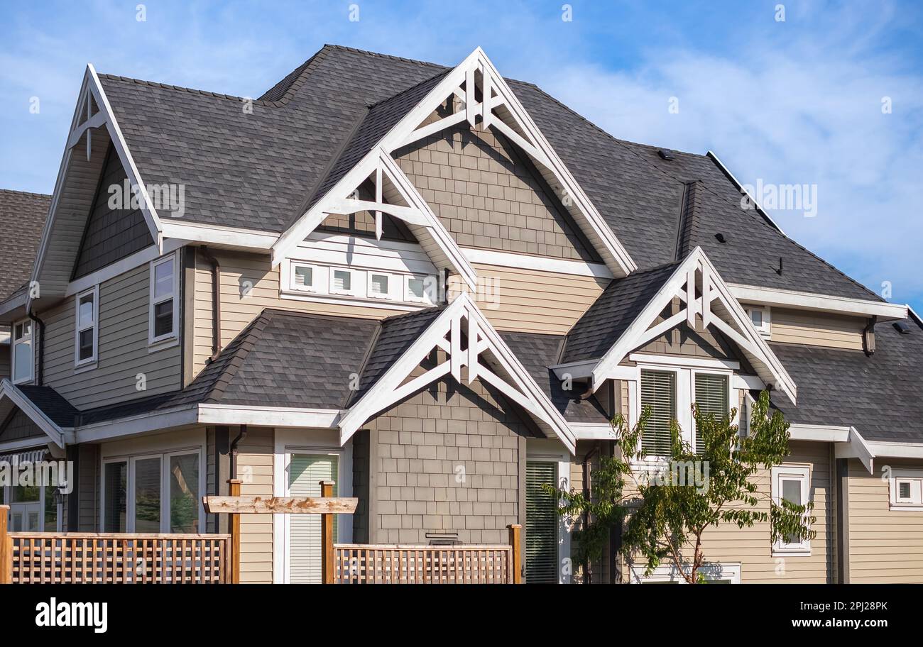 Houses with shingle roof against blue sky. Edge of roof shingles on top ...