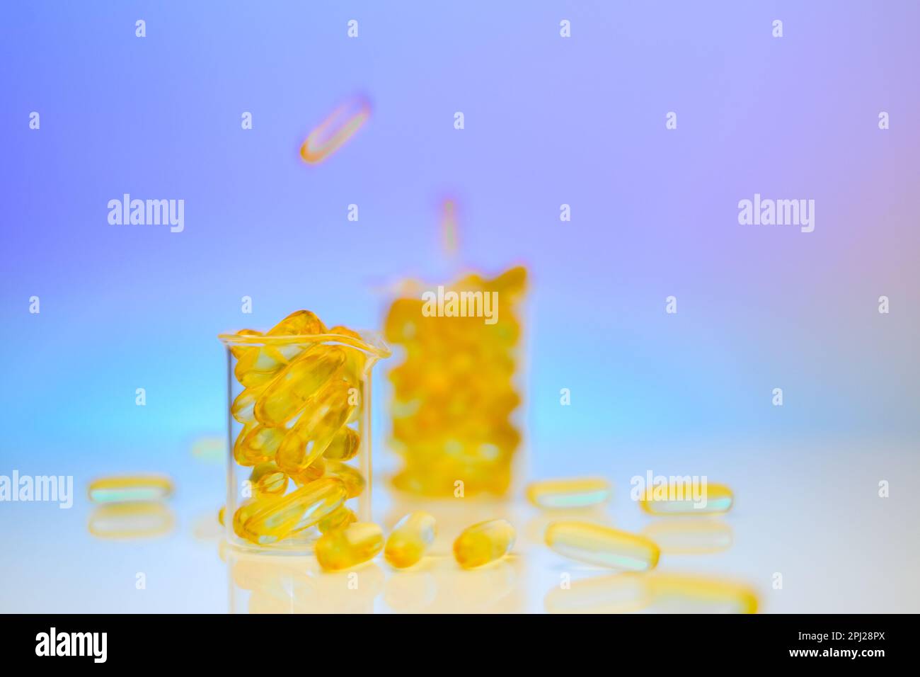 Yellow fatty acids oil capsules in containers on a blue background ...