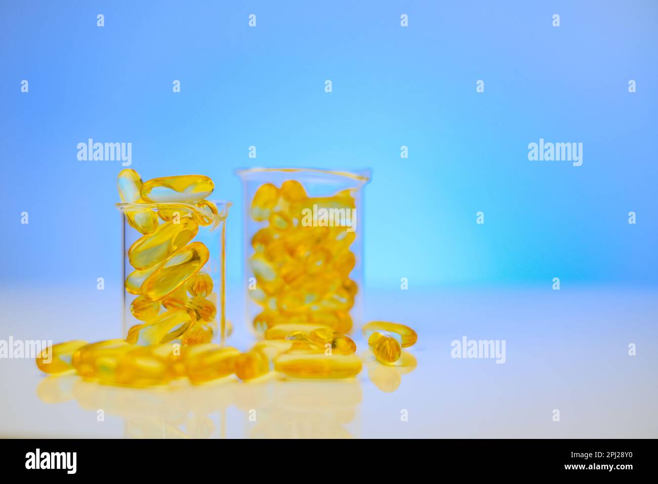 Fish oil capsules in transparent flasks on a blue background.Natural ...