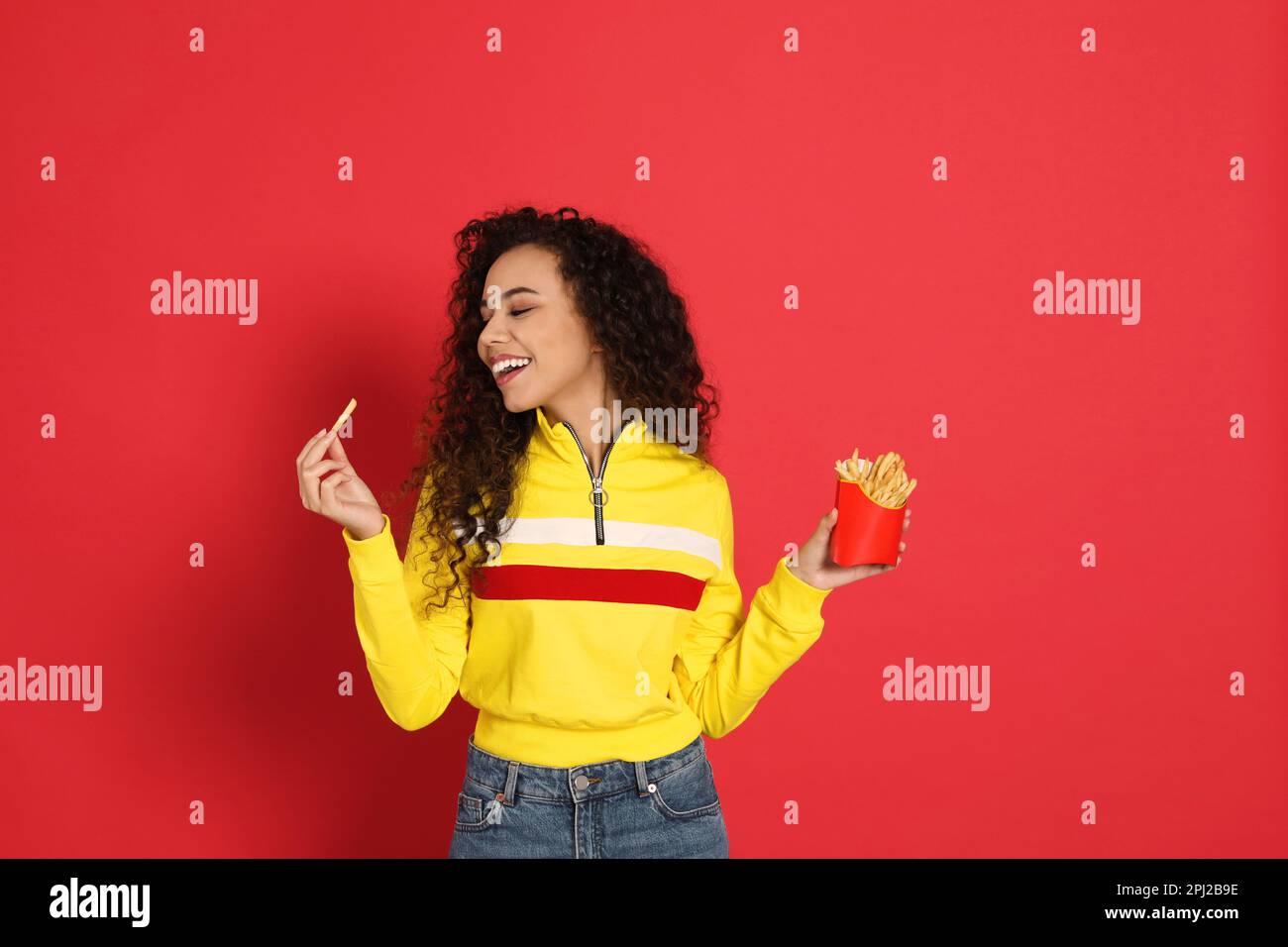 African American woman eating French fries on red background Stock ... African American woman eating French fries on red background Stock ...