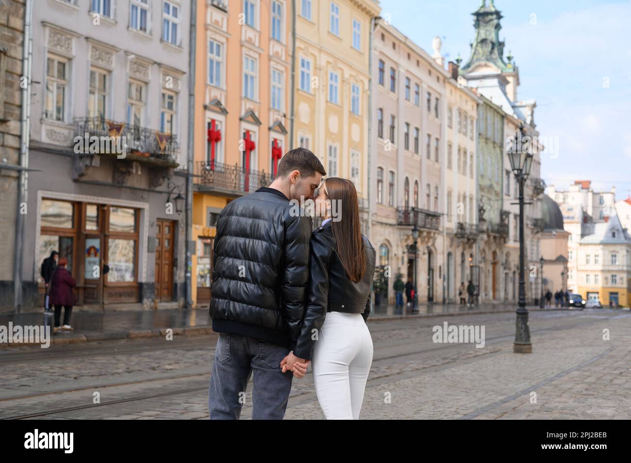 Lovely young couple walking along tram track on pavement road, back ...