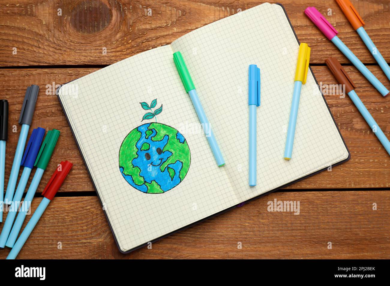 Happy Earth Day. Notebook with drawing of planet and markers on wooden ...