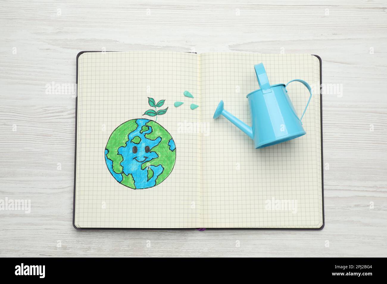 Happy Earth Day. Notebook with drawing of planet and watering can on ...