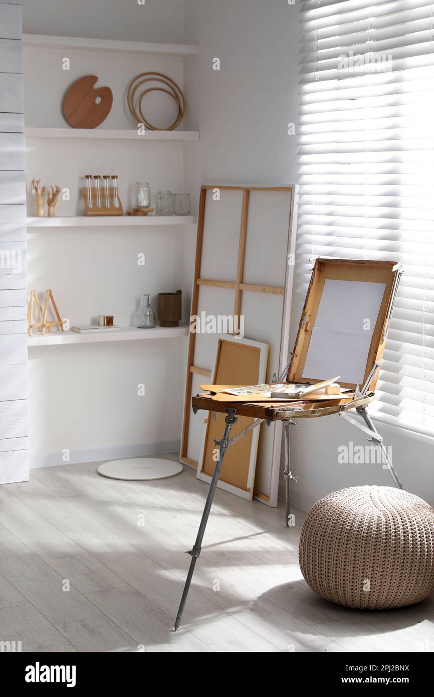 Modern studio interior with artist's workplace and wooden easel near ...
