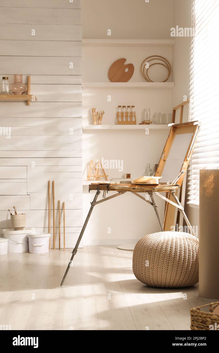 Modern studio interior with artist's workplace and wooden easel near ...