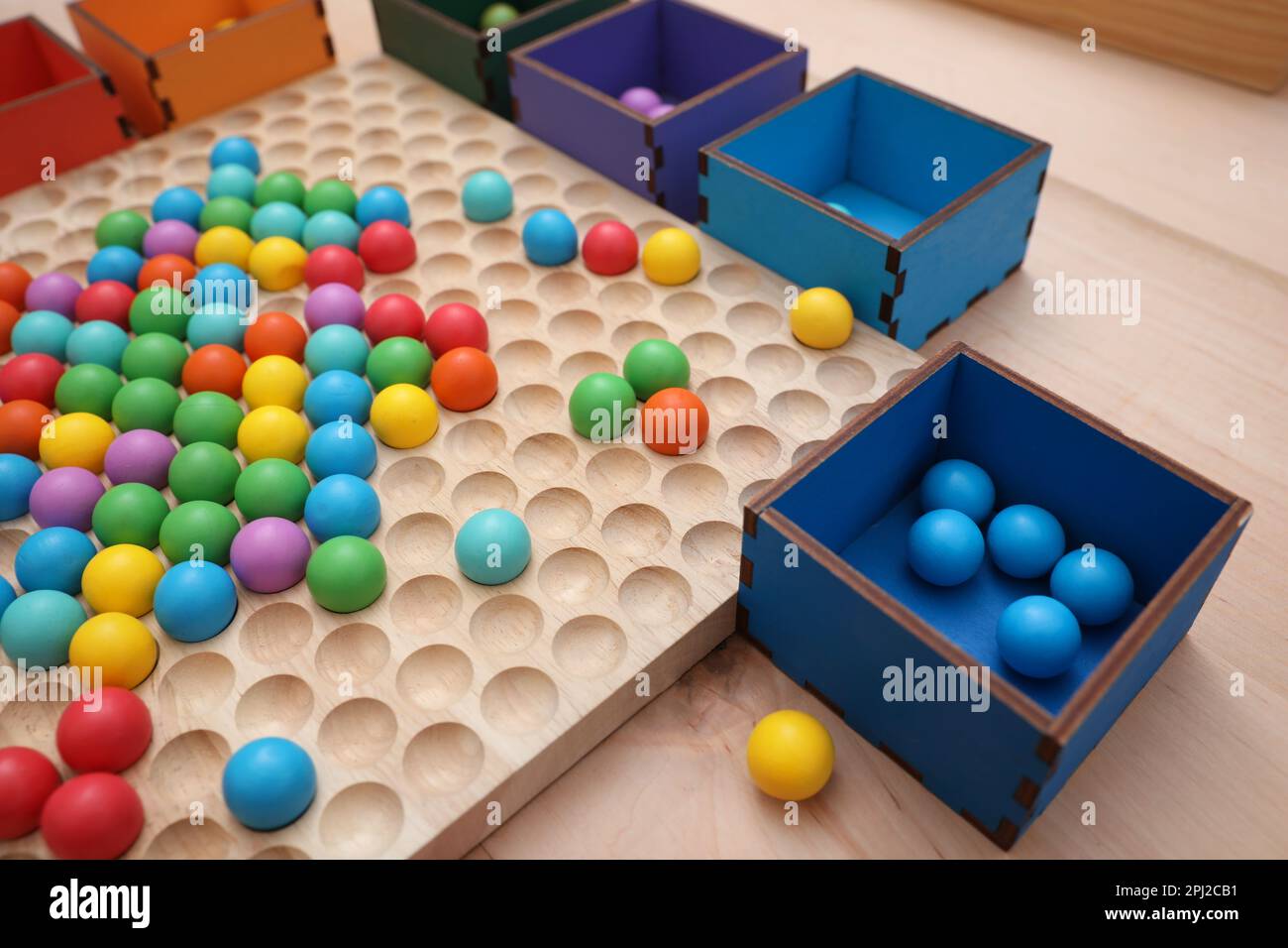 Wooden sorting board and boxes with colorful balls on table, closeup ...