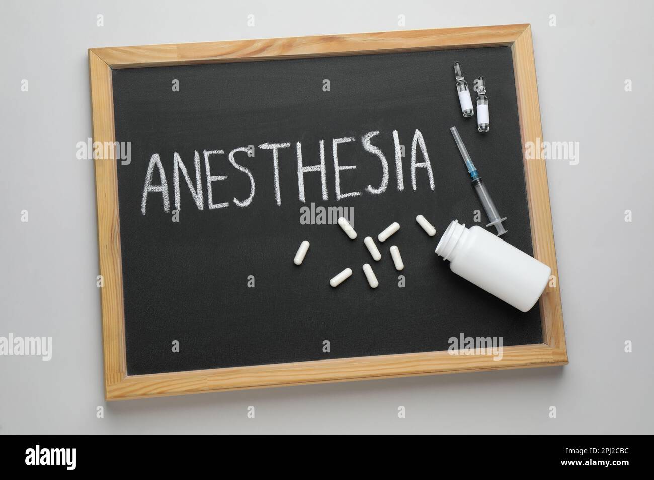 Blackboard with word Anesthesia, syringe and drugs on light grey ...