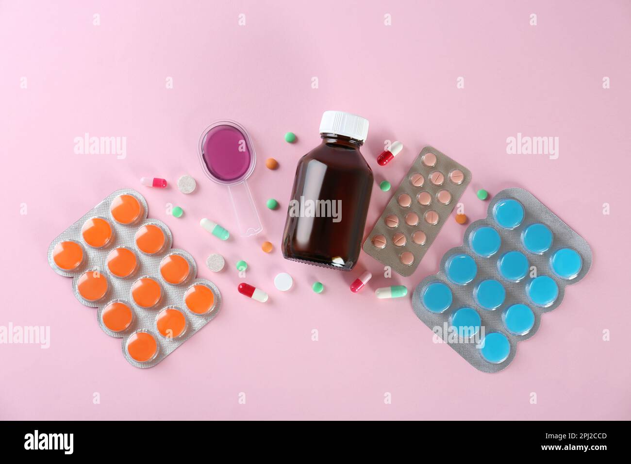 Flat lay composition with cough drops, syrup and pills on pink ...