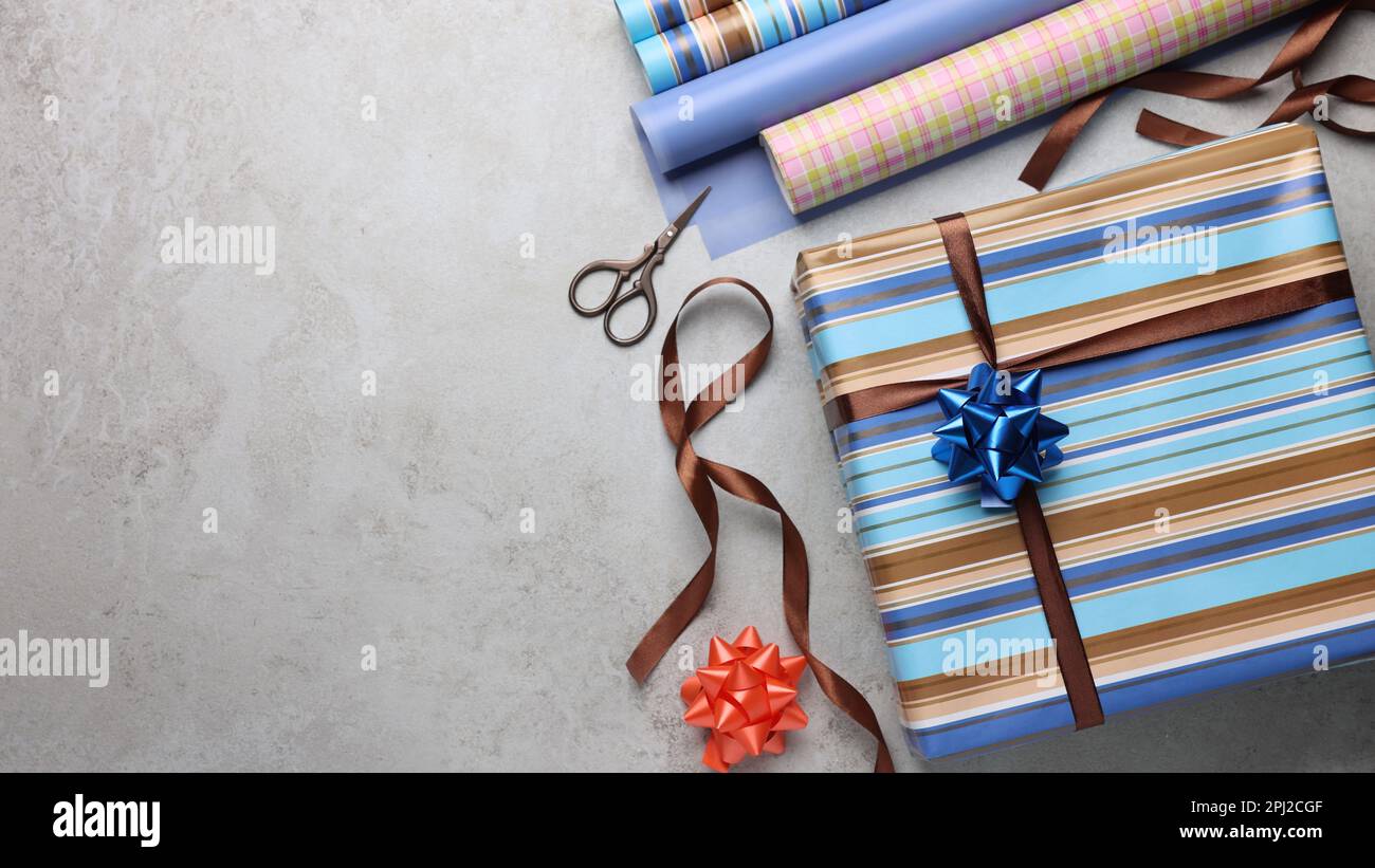 Flat lay composition with beautifully wrapped gift box on grey table ...